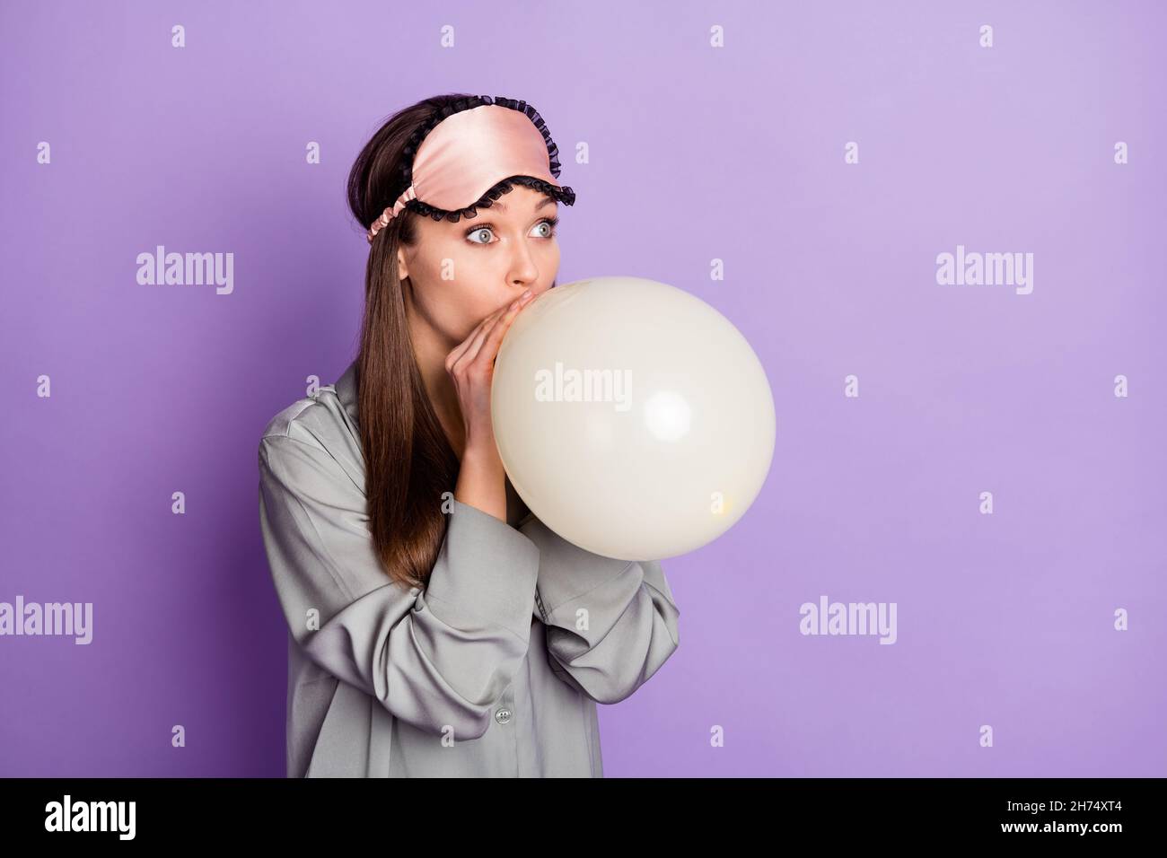 Photo portrait of woman in pajama sleeping mask blowing air balloon ...