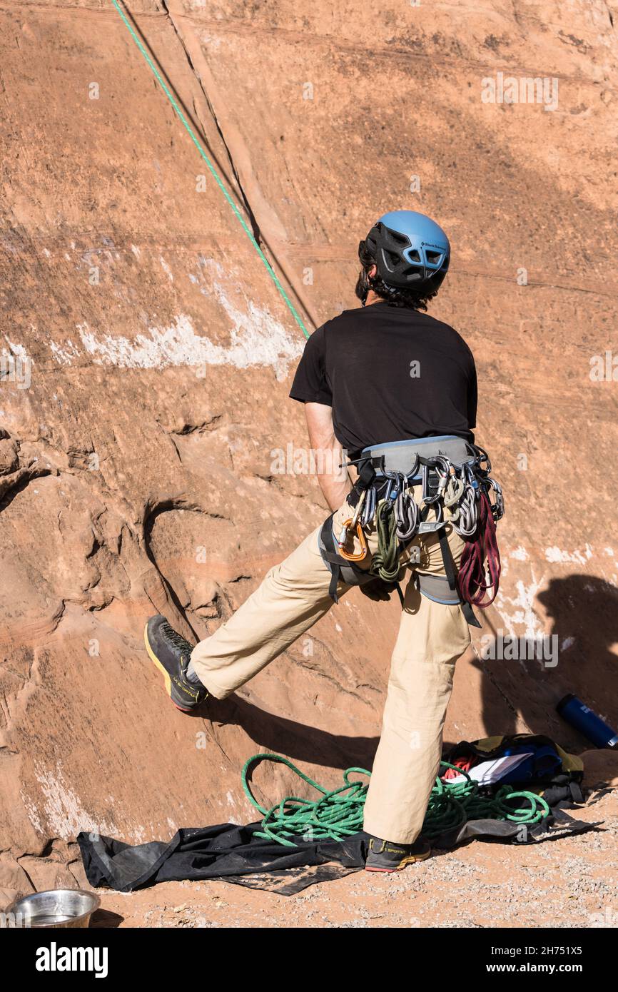 A rock climber belays a another climber on the climbing route above him ...