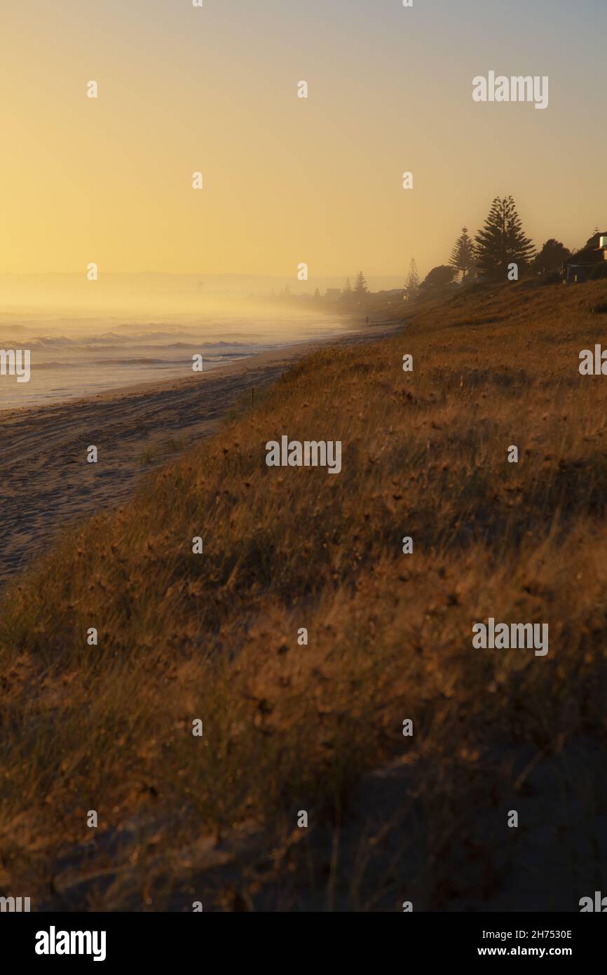 Vertical breathtaking view of the sunset at the beach on a steamy day ...