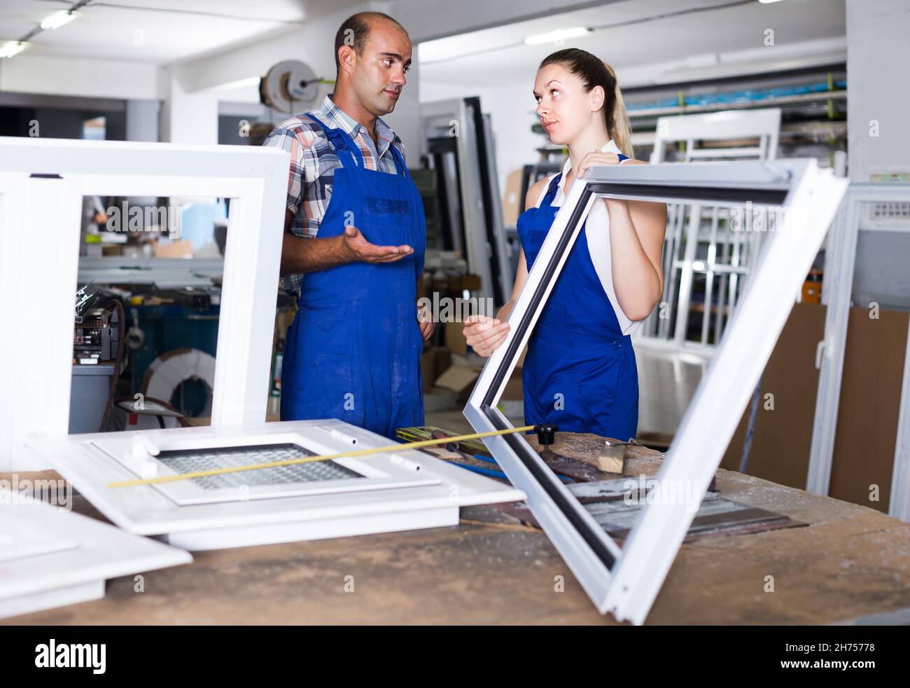 Foreman explaining plastic windows assembly process to young female ...