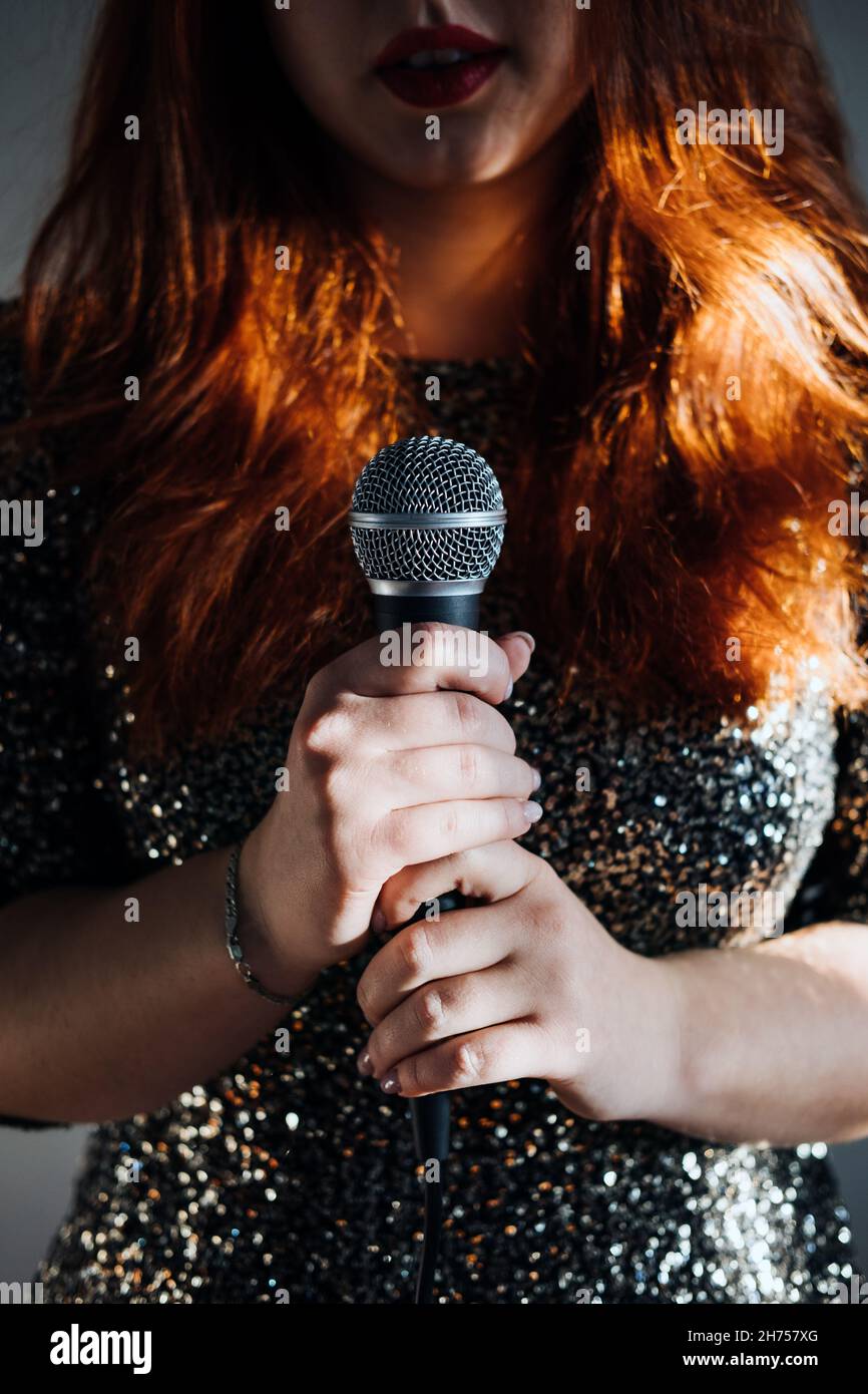 Faceless portrait of redhead woman in sparkly evening dress holding ...