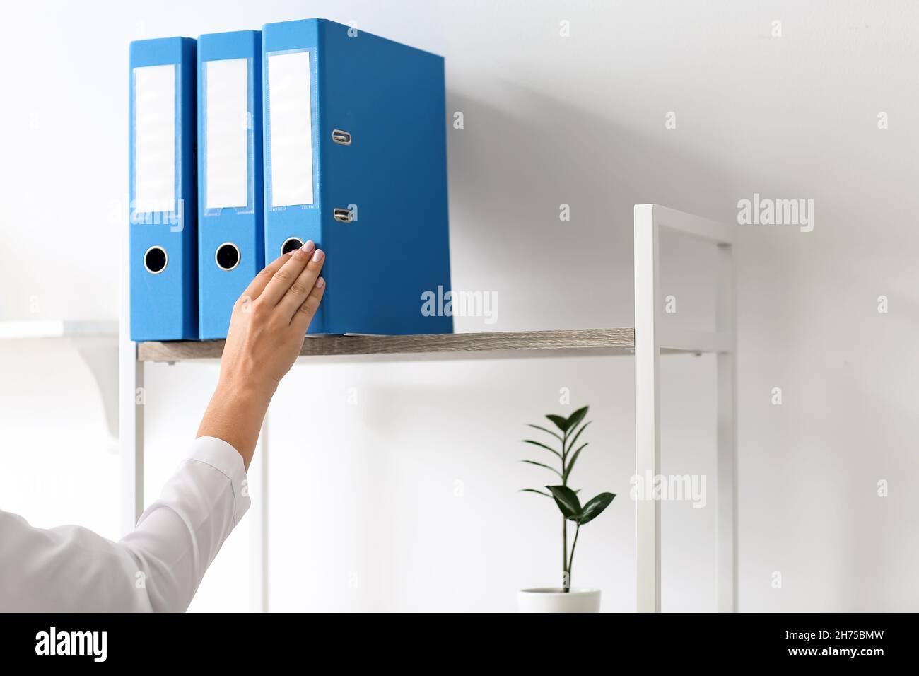 Female doctor taking folder from shelf in clinic Stock Photo - Alamy