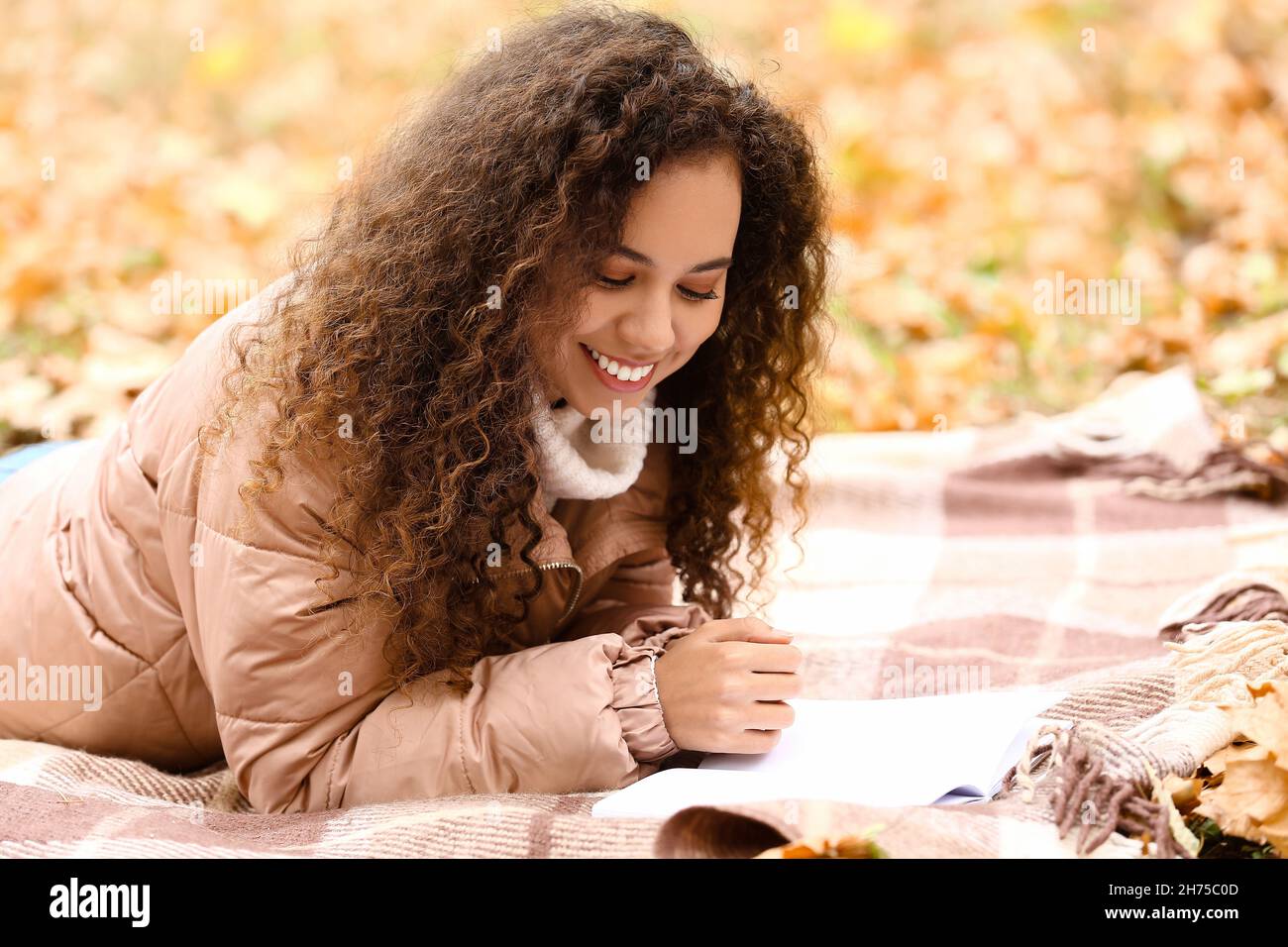 Beautiful African-American woman reading book with blank pages on plaid ...