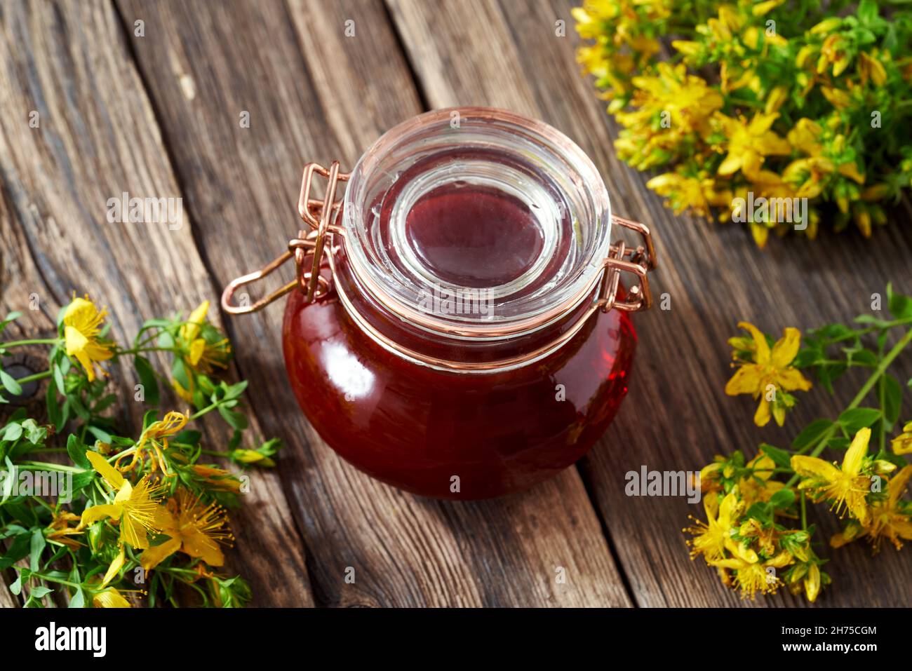 A bottle of red oil made from St. John's wort flowers, with fresh ...