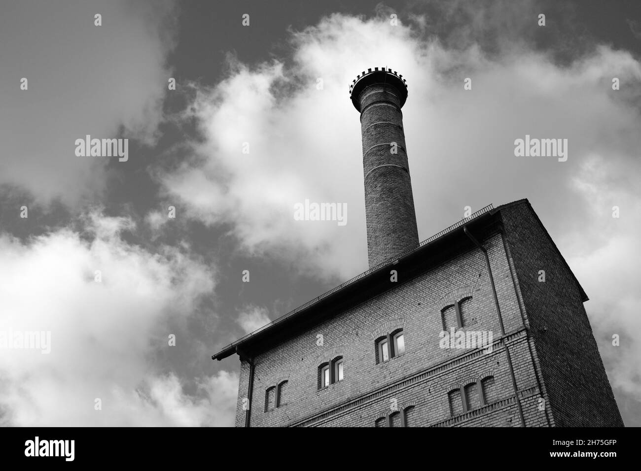 Low angle grayscale shot of an old factory building with a tall tower ...