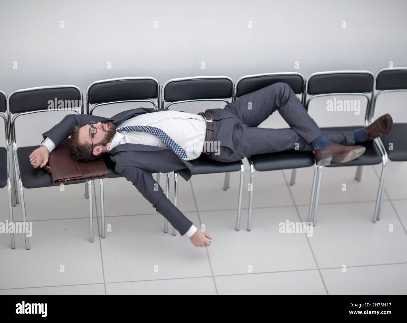 young businessman sleeping on chairs in the office hallway Stock Photo ...
