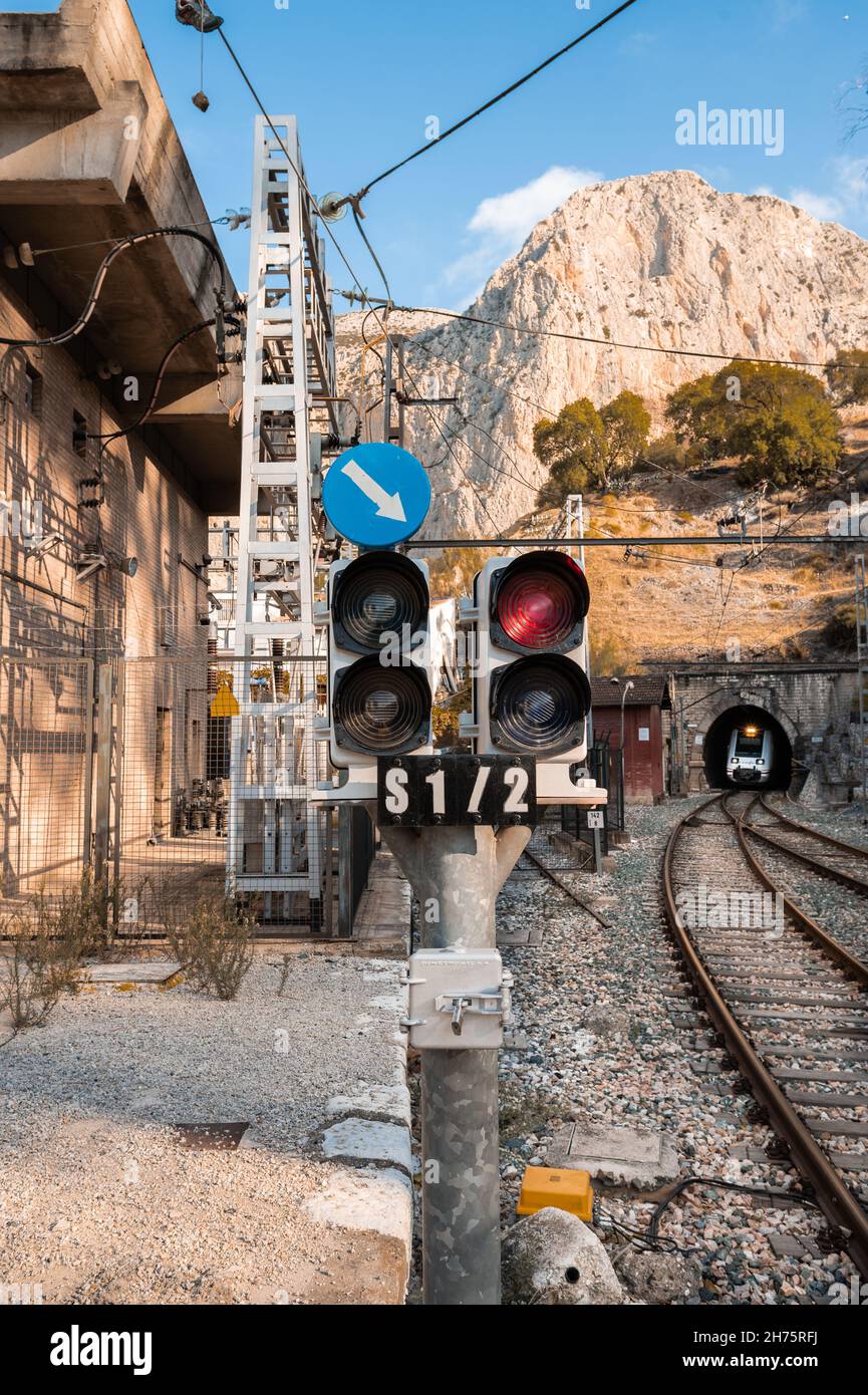 Vertical shot of railway signals with a train coming out of a tunnel in ...