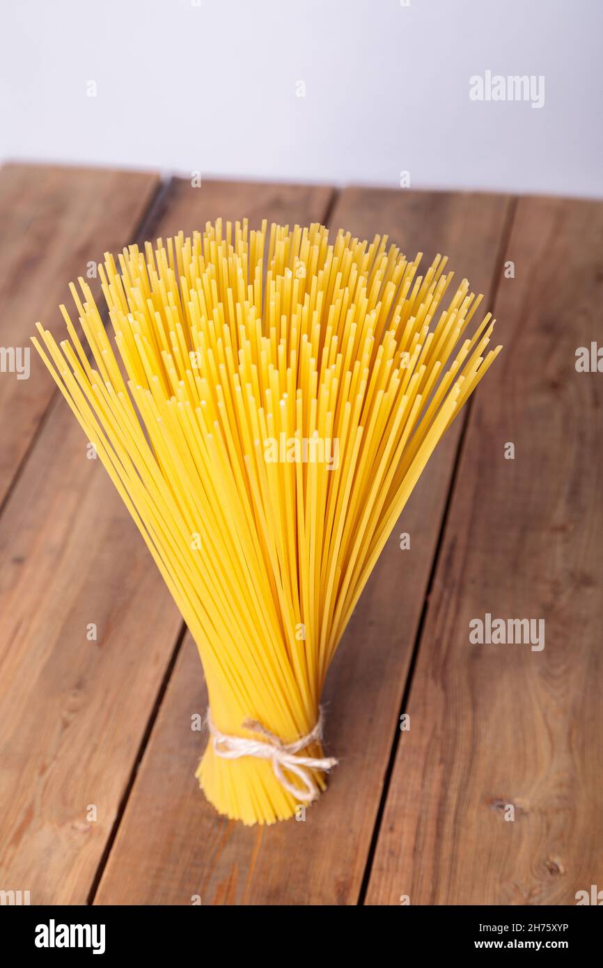 A vertical bunch and a bunch of raw spaghetti tied with string. Bundle ...