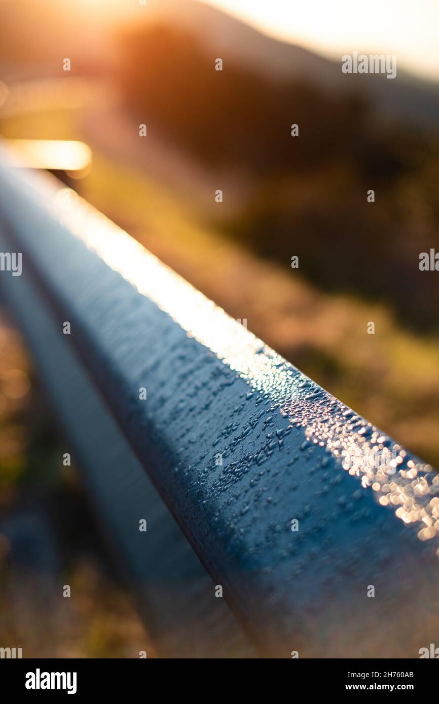 Some moist cold morning dew on a blue metal bench while yellow sunrise ...
