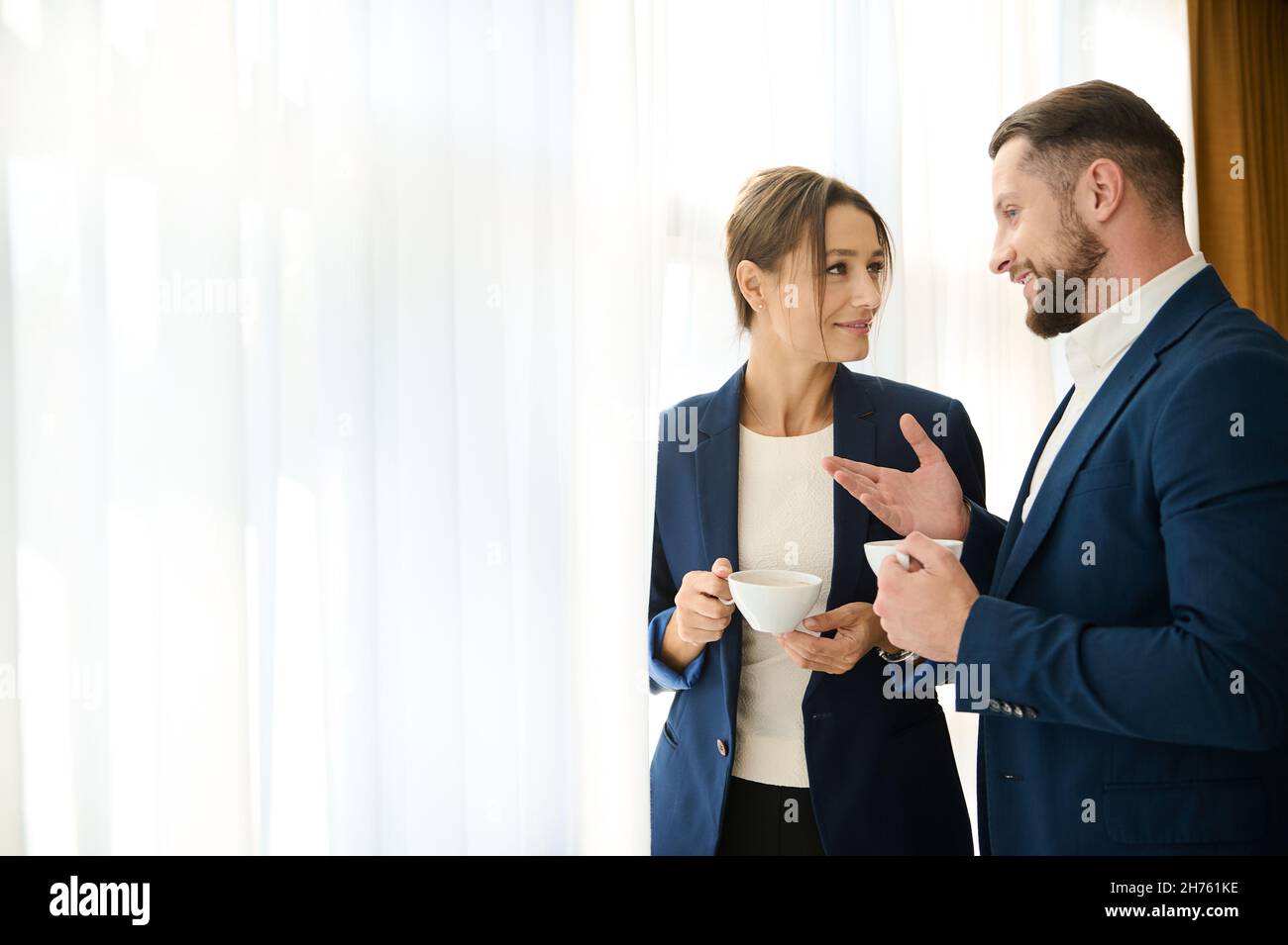 Two business partners talking to each other over a cup of coffee ...