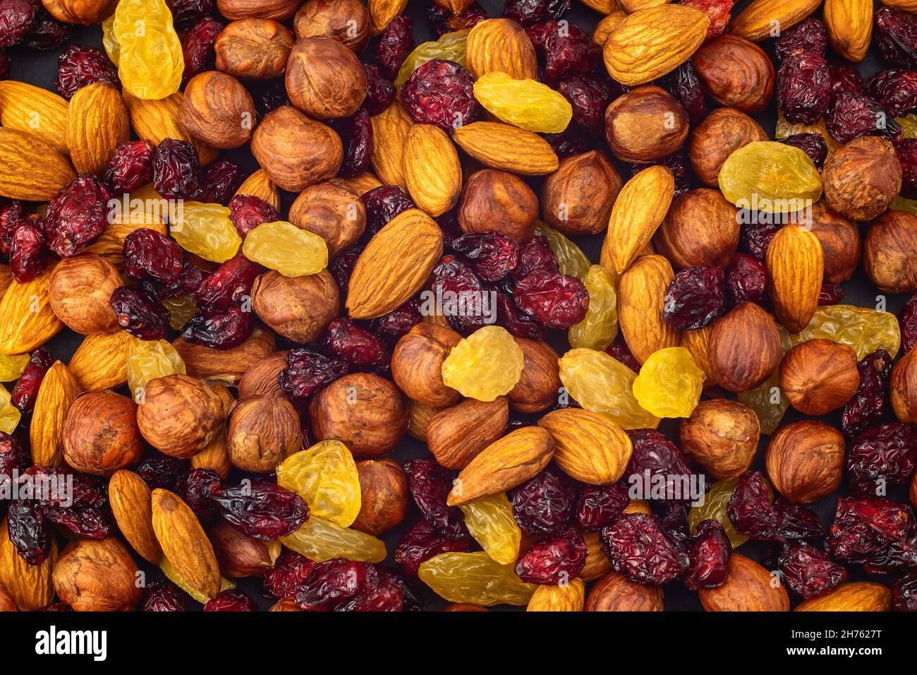Mixed dried fruits background. Healthy snacks. Almonds, raisins, hazelnuts, cranberries ...