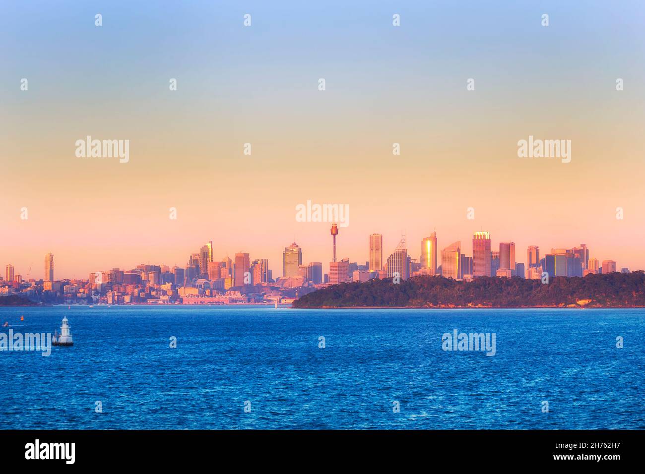Distant Sydney city CBD skyline on shores of Sydney harbour in warm ...
