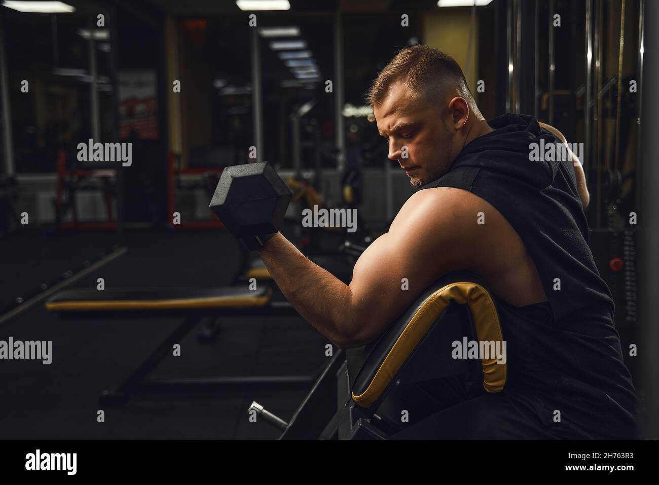 Bodybuilder with big muscles and broad back trains in the gym with ...