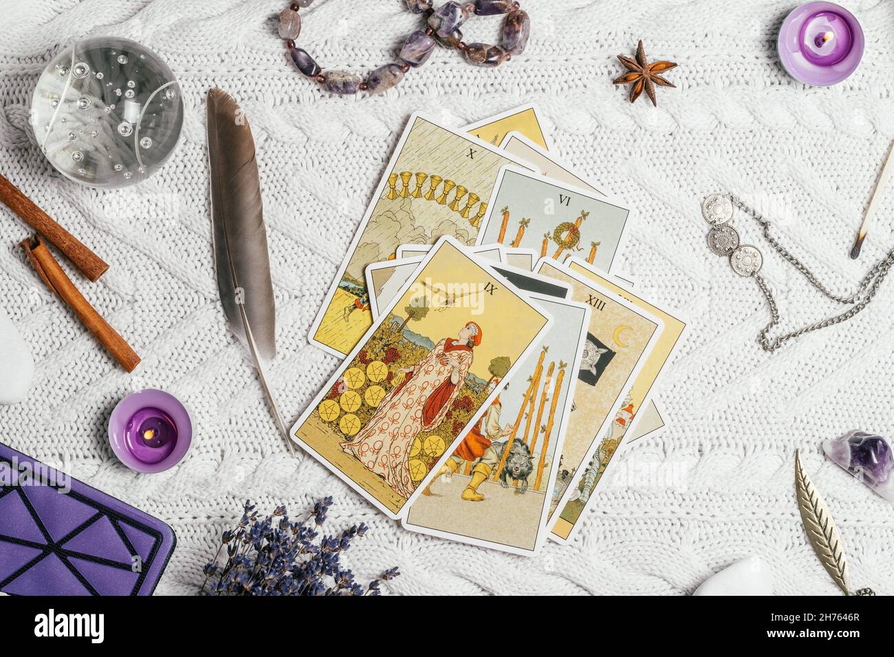 Tarot cards spread face up on white knitted surface with crystal ball ...