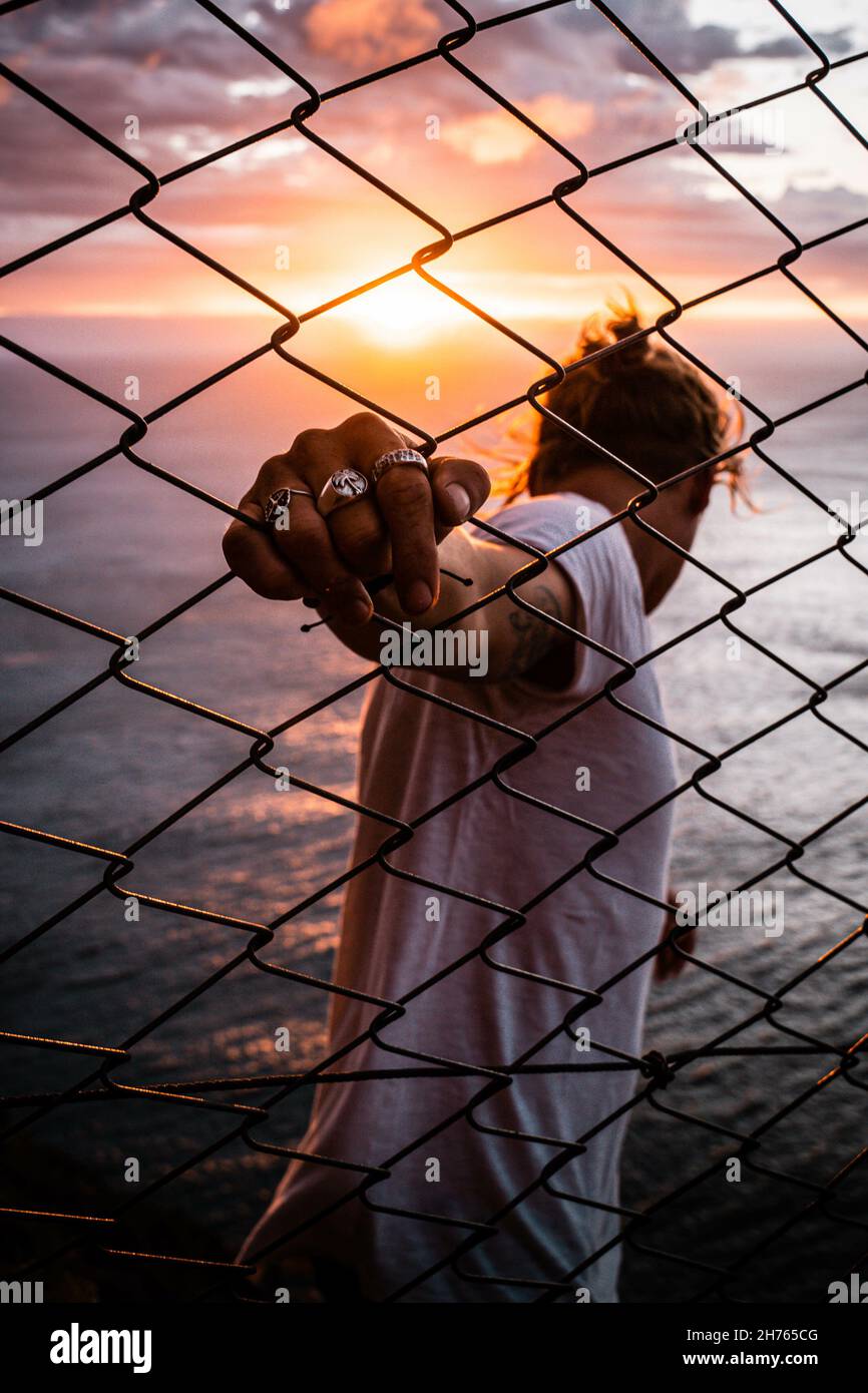 Vertical back view of a male holding a grid fence on the body of the ...