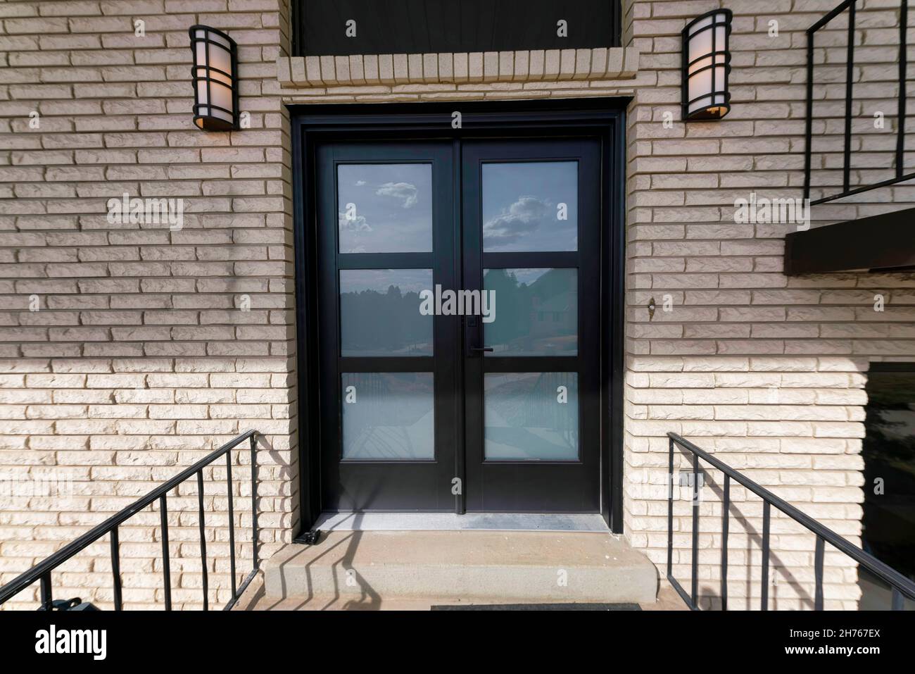 Black double doors with reflective glass panels and modern wall ...