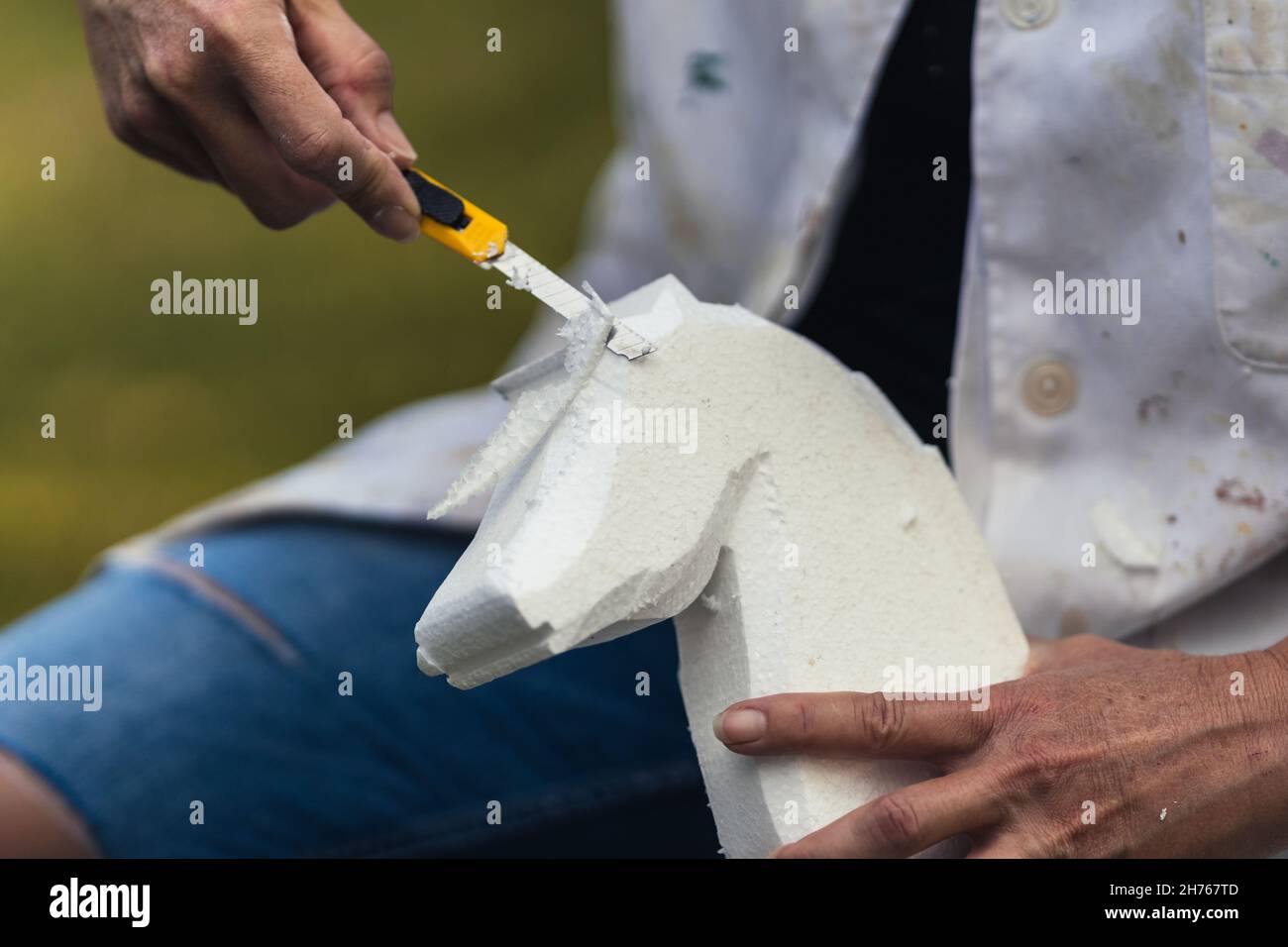 Person shaping a piece of polystyrene to create the figure of an animal ...