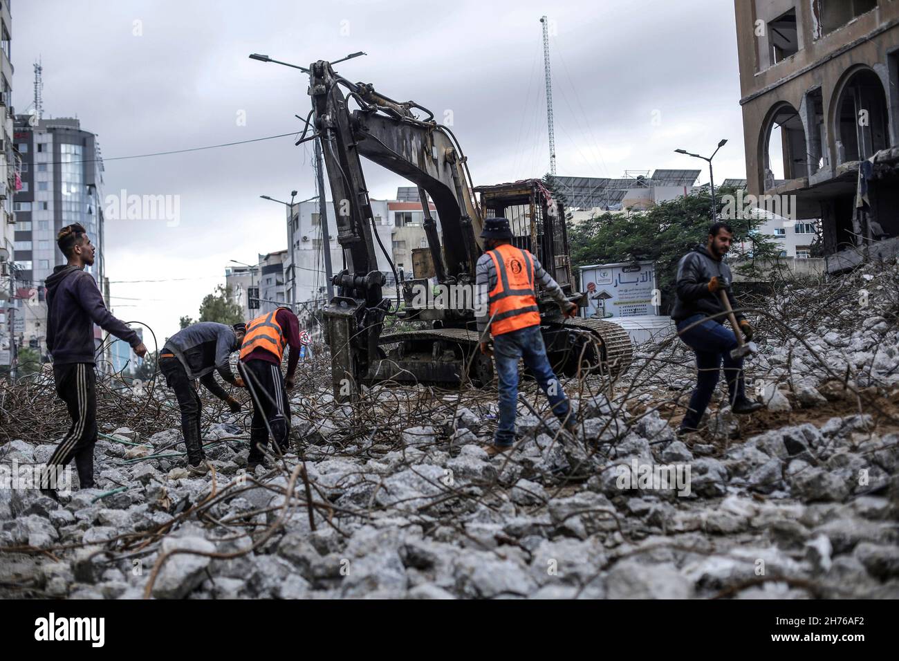 Palestinian workers remove the rubble of the Al-Jawhara Tower in the Al ...
