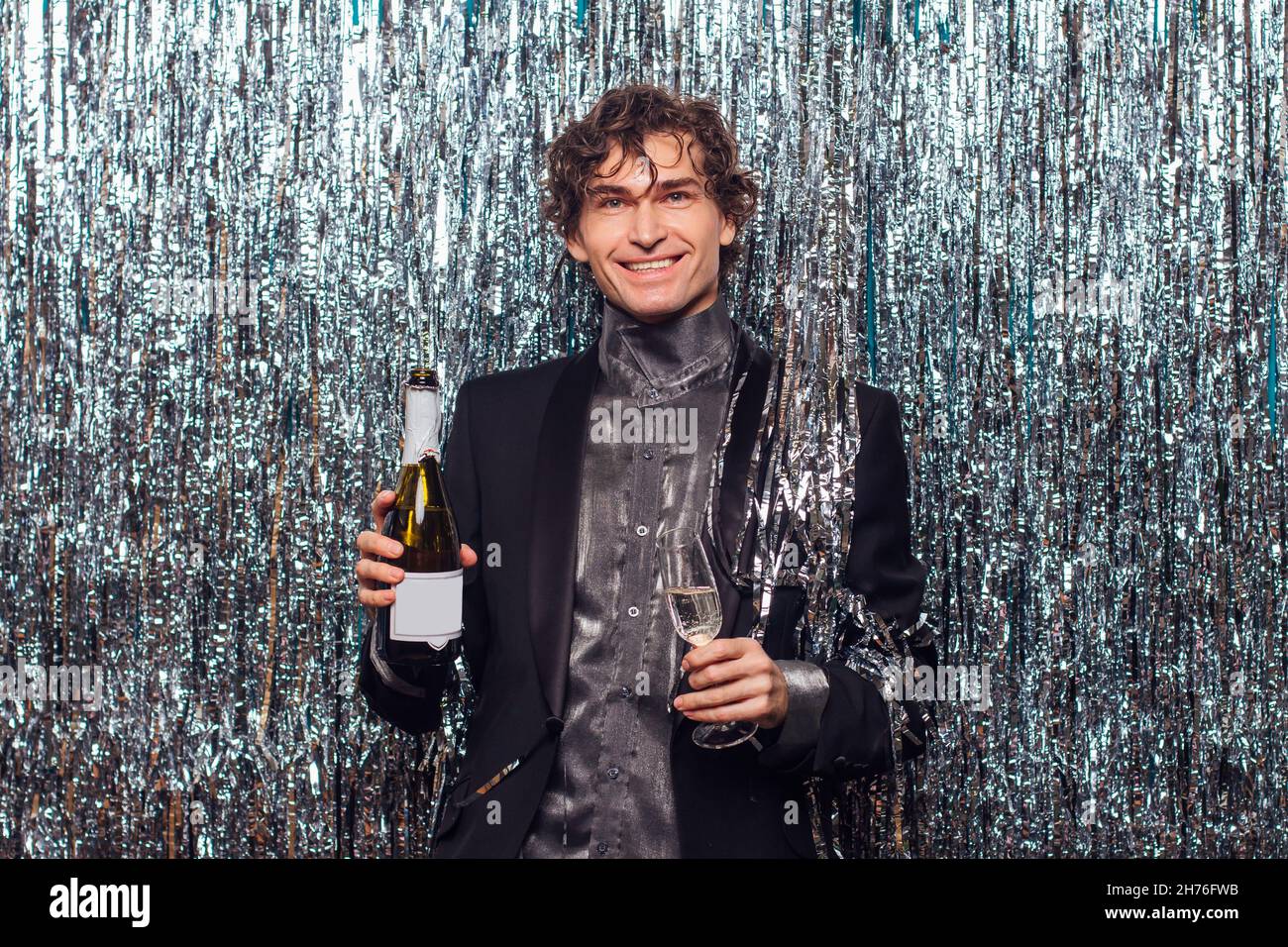 Happy tipsy man with bottle of champagne and wine glass at christmas or ...