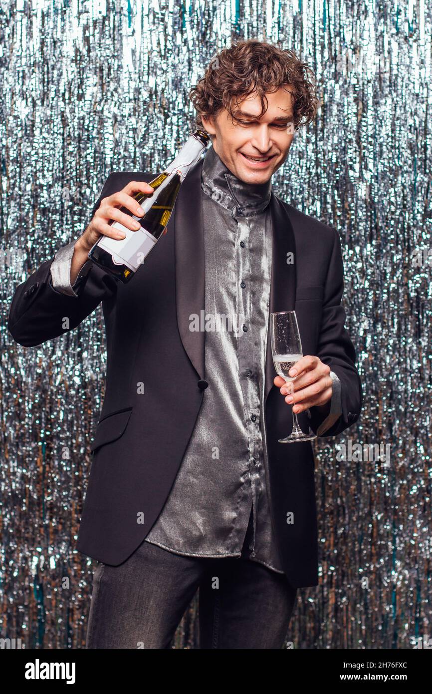 Happy tipsy man with bottle of champagne and wine glass at christmas or ...