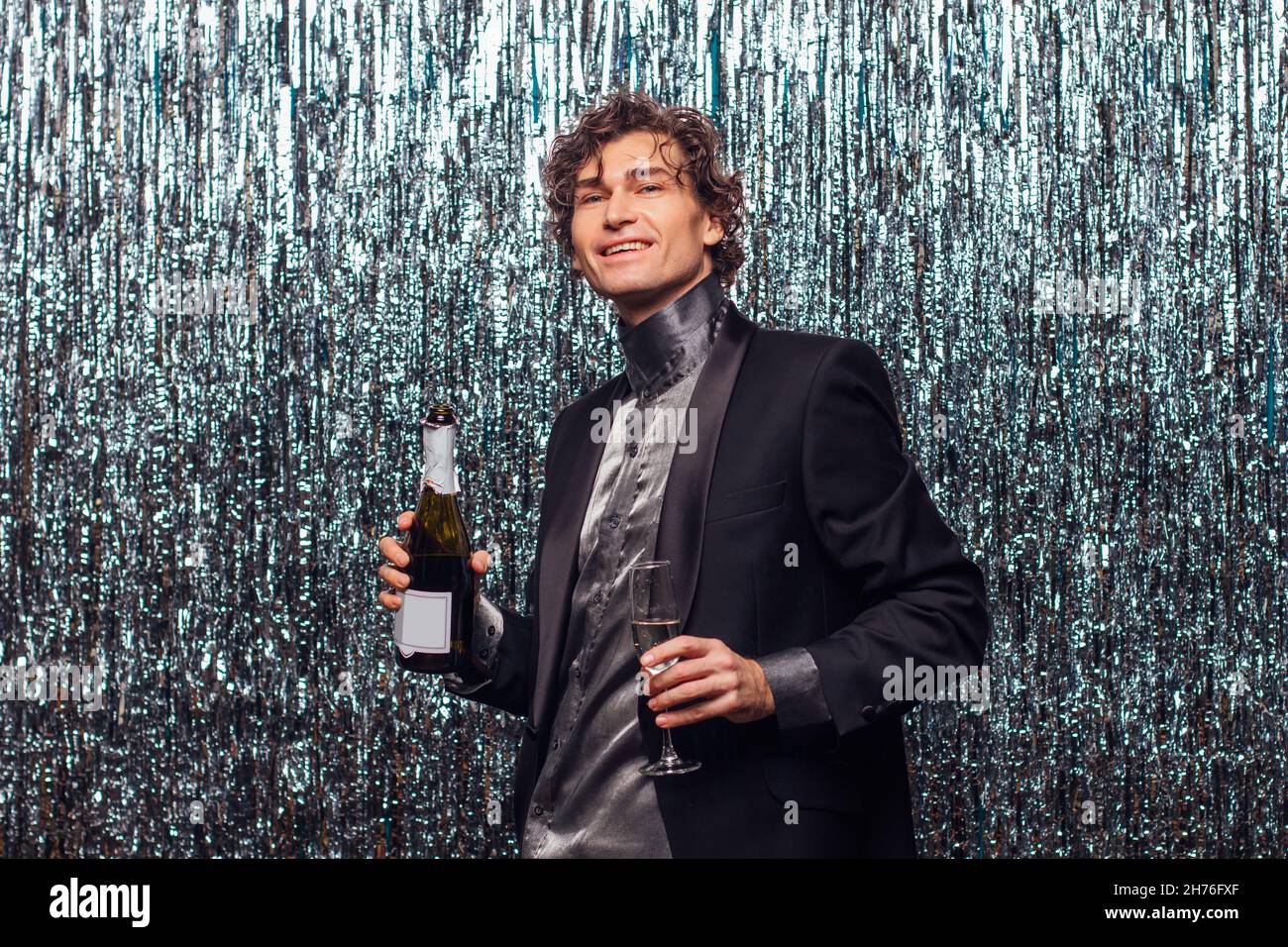 Happy tipsy man with bottle of champagne and wine glass at christmas or ...