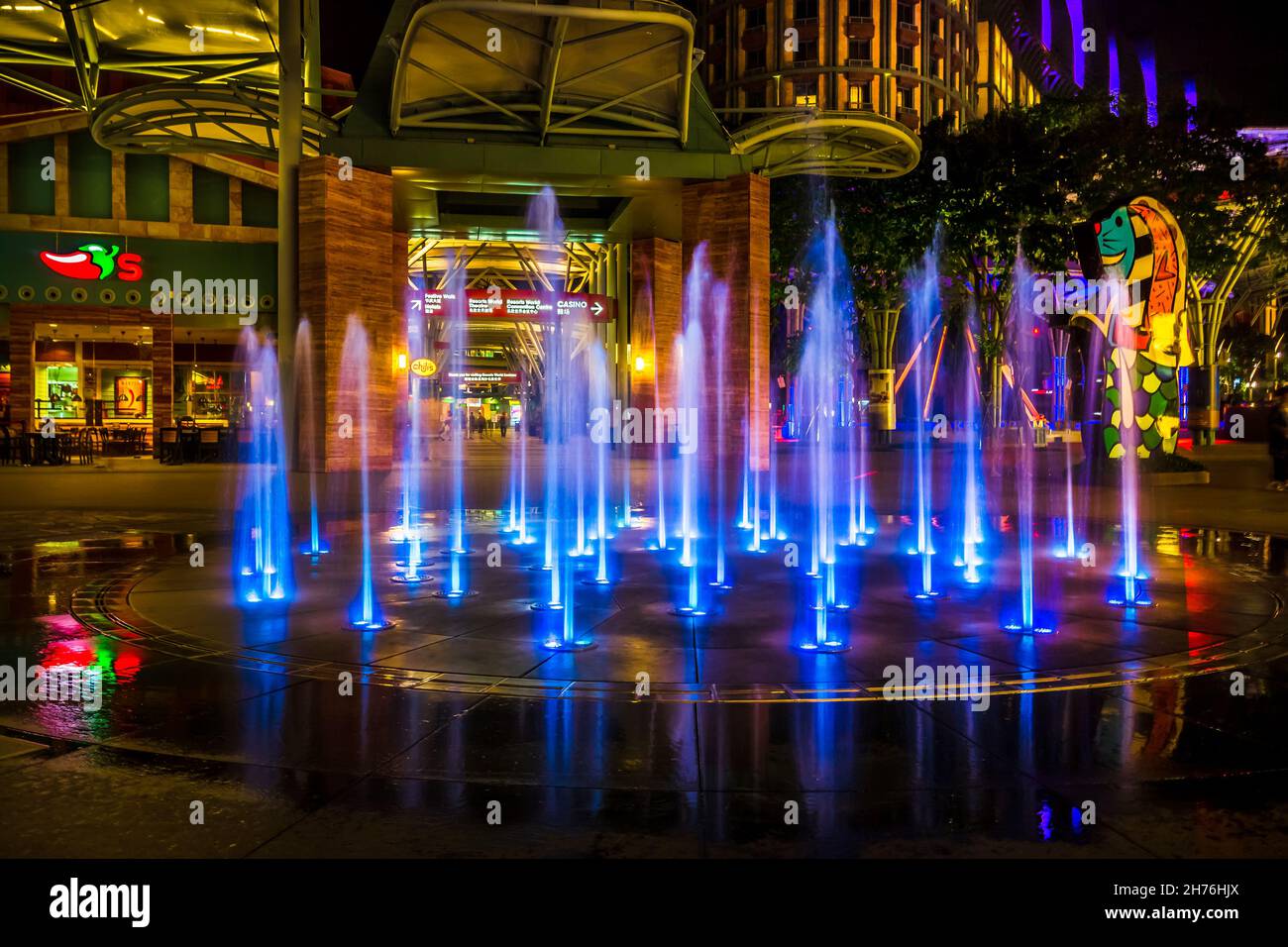 Blue colored fountain jets from the floor with water reflection, Resort ...