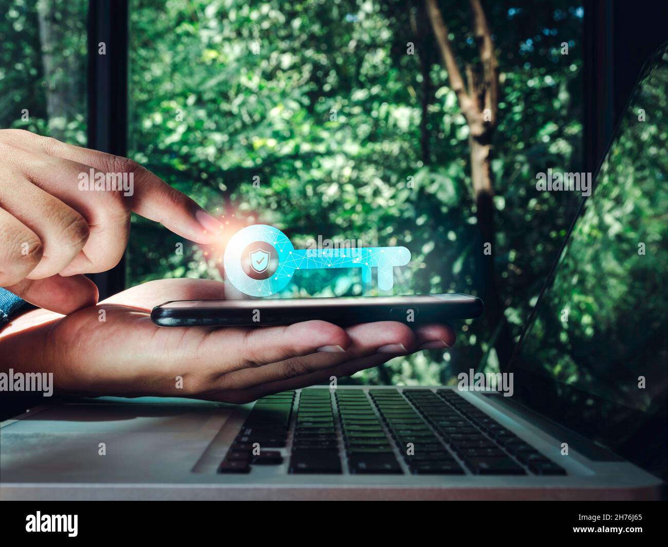 Two steps authentication concept. Virtual key icon on smartphone in hand with laptop for ...
