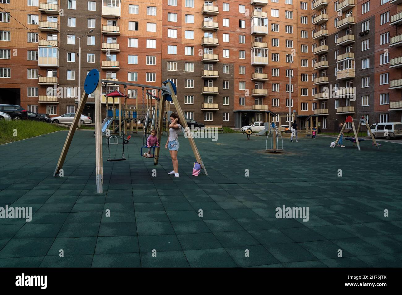 Parents with children play on the playground in the common courtyard of ...