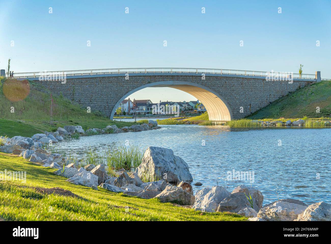 Arched bridge over the Oquirrh Lake with rocks on the shore at Daybreak ...