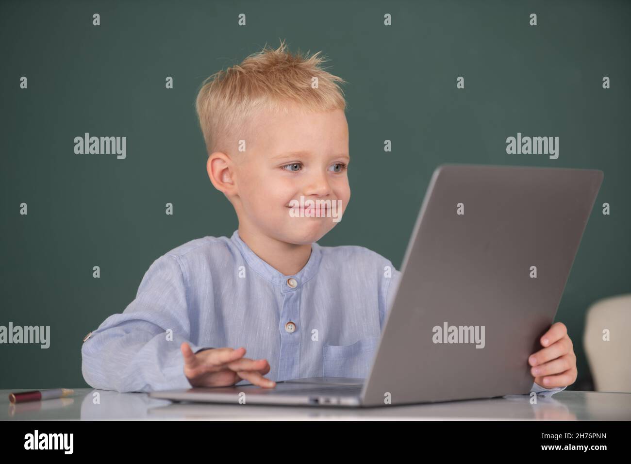 Portrait of attractive cheerful boy using laptop. Little funny ...