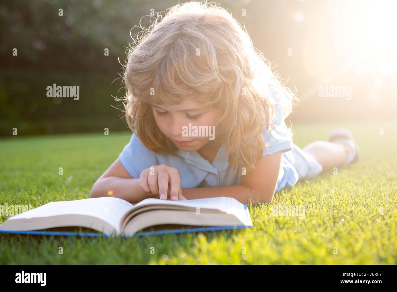 Beautiful child boy book on grass background. Kids reading book in park ...