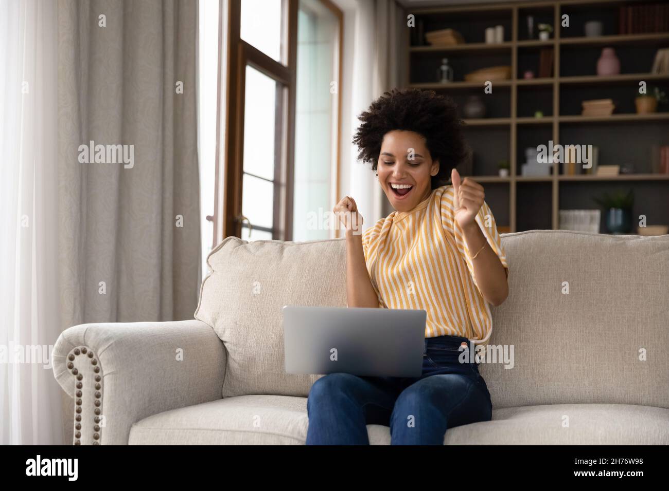 Excited cheerful young Black woman using laptop computer Stock Photo ...