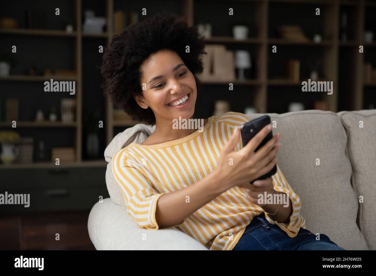 Happy millennial Black girl getting nice text message on smartphone ...