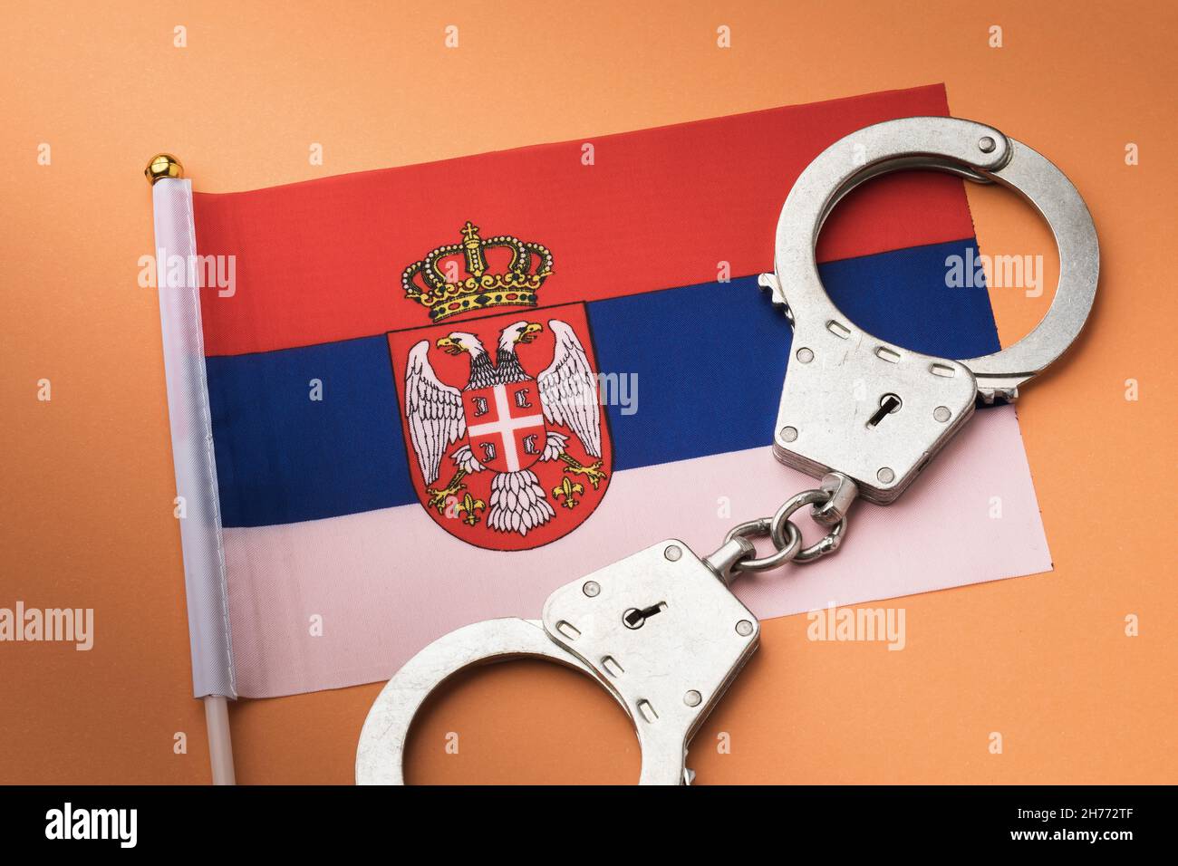 Serbian flag and handcuffs on a colored background, the concept of ...
