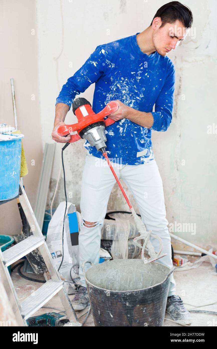 Builder mixing plaster in bucket using electric mixer Stock Photo - Alamy