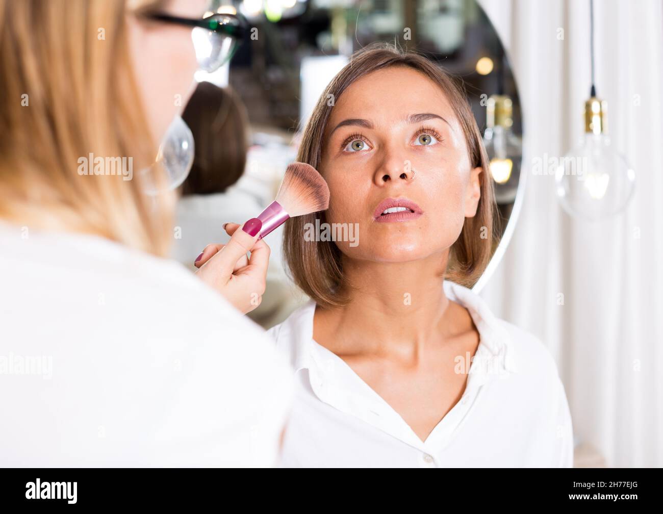 female makeup artist applying cosmetics for woman Stock Photo - Alamy