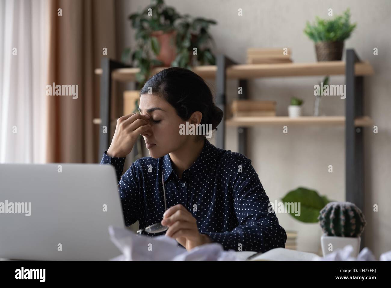 Overworked stressed young Indian businesswoman suffering from eyestrain ...