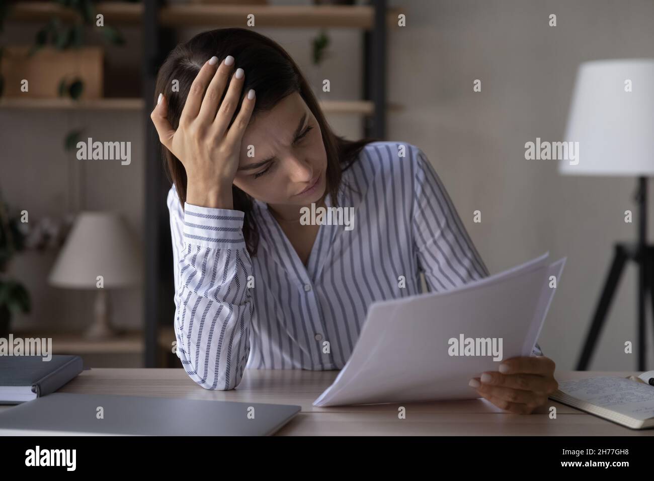 Unhappy young 25s businesswoman reading paper letter with bad news ...
