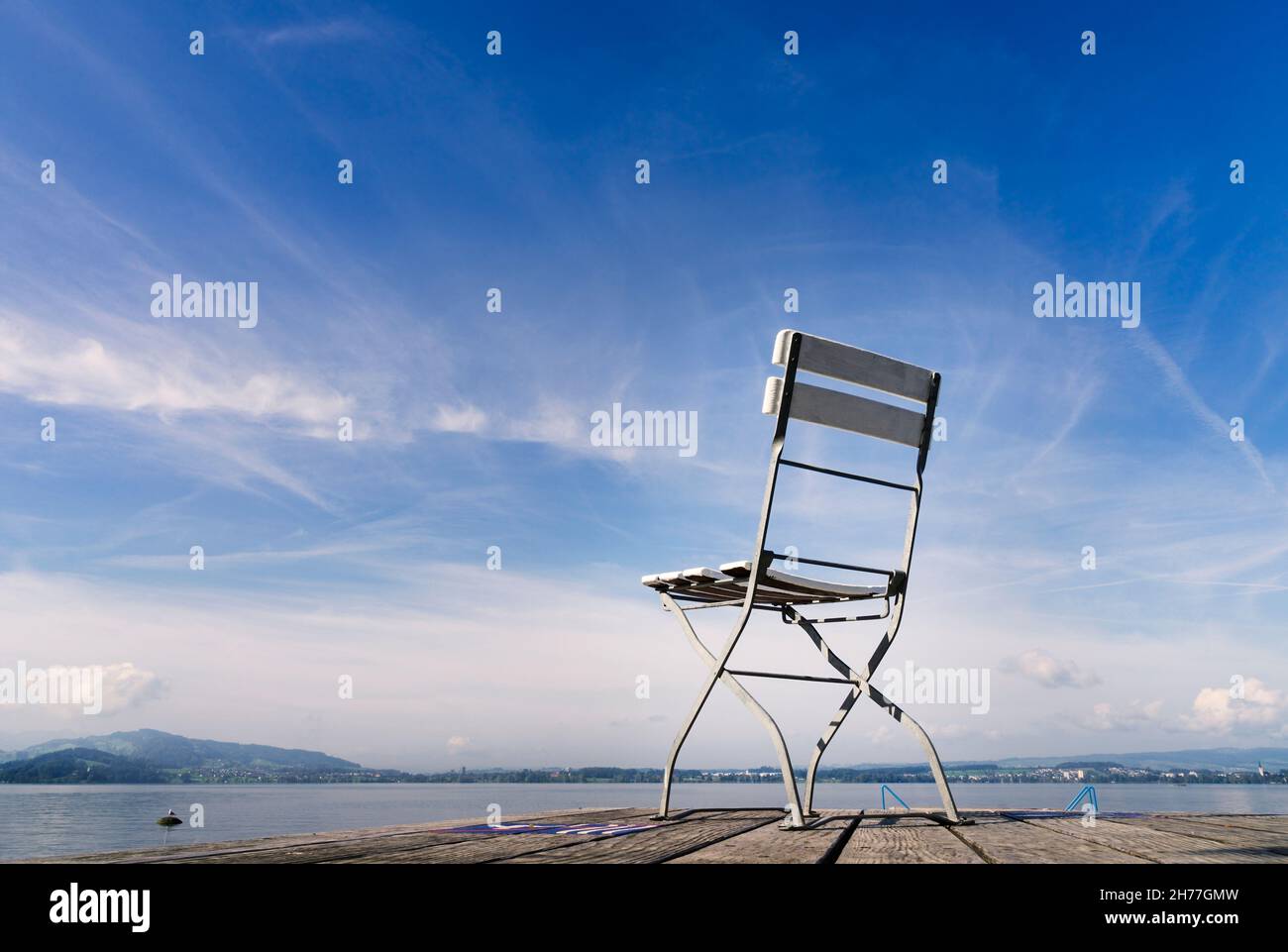 View of a lonely and empty chair with a landscape of a calm lake with ...