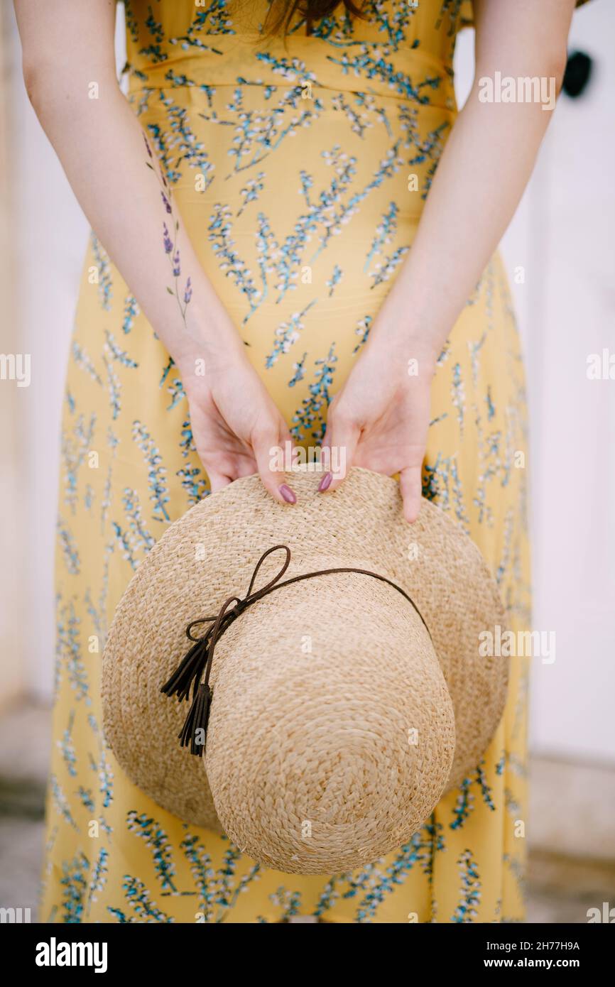 Girl holding a straw hat behind her back Stock Photo - Alamy
