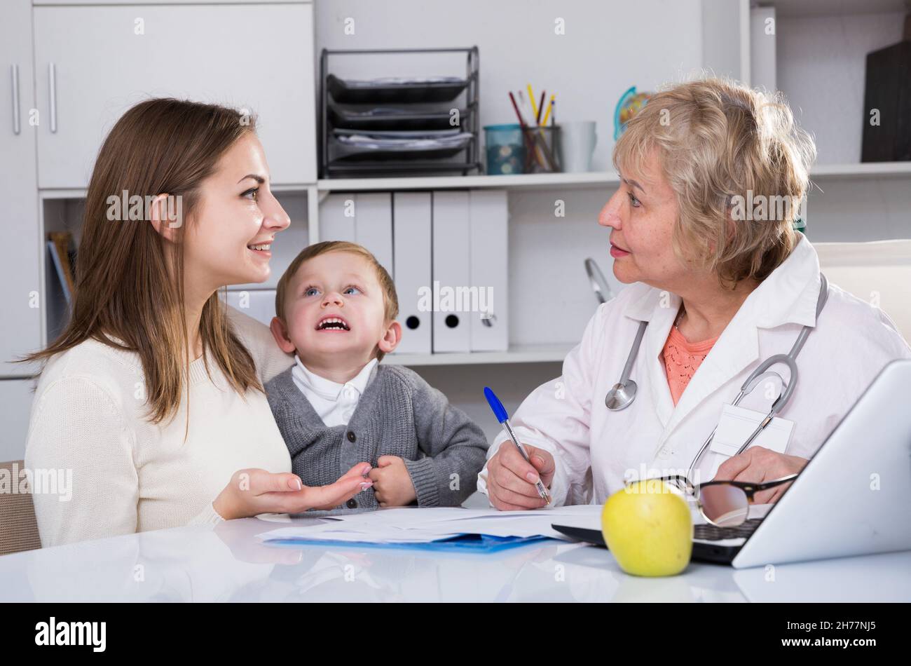 Pediatrist woman is examining kid and talking to his mother about it ...