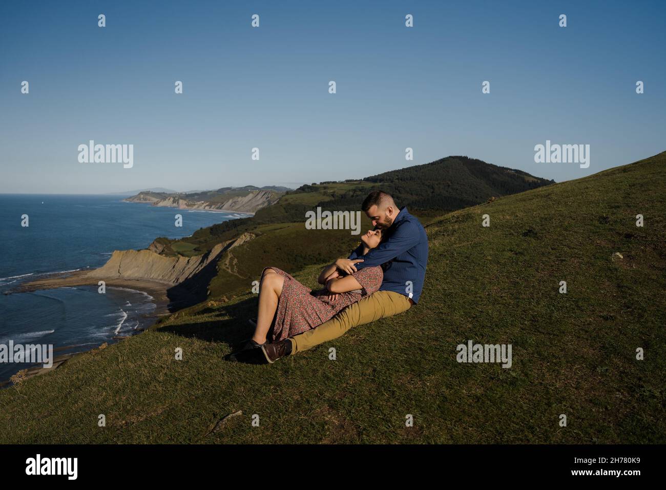 A cute young couple sitting on the grass on a cliff Stock Photo - Alamy