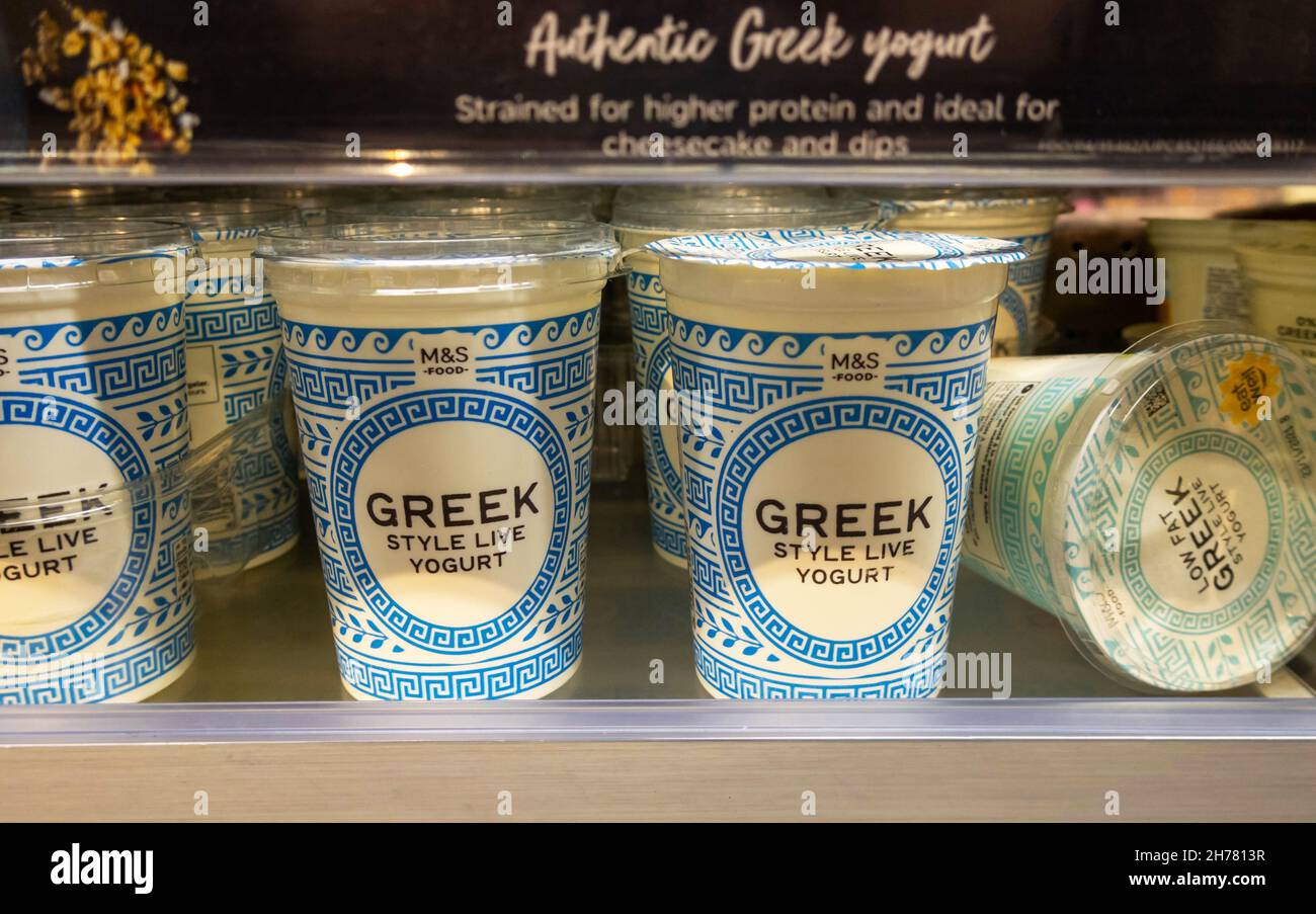 Containers of Greek-style live yogurt on a shelf at an M&S Foodhall ...