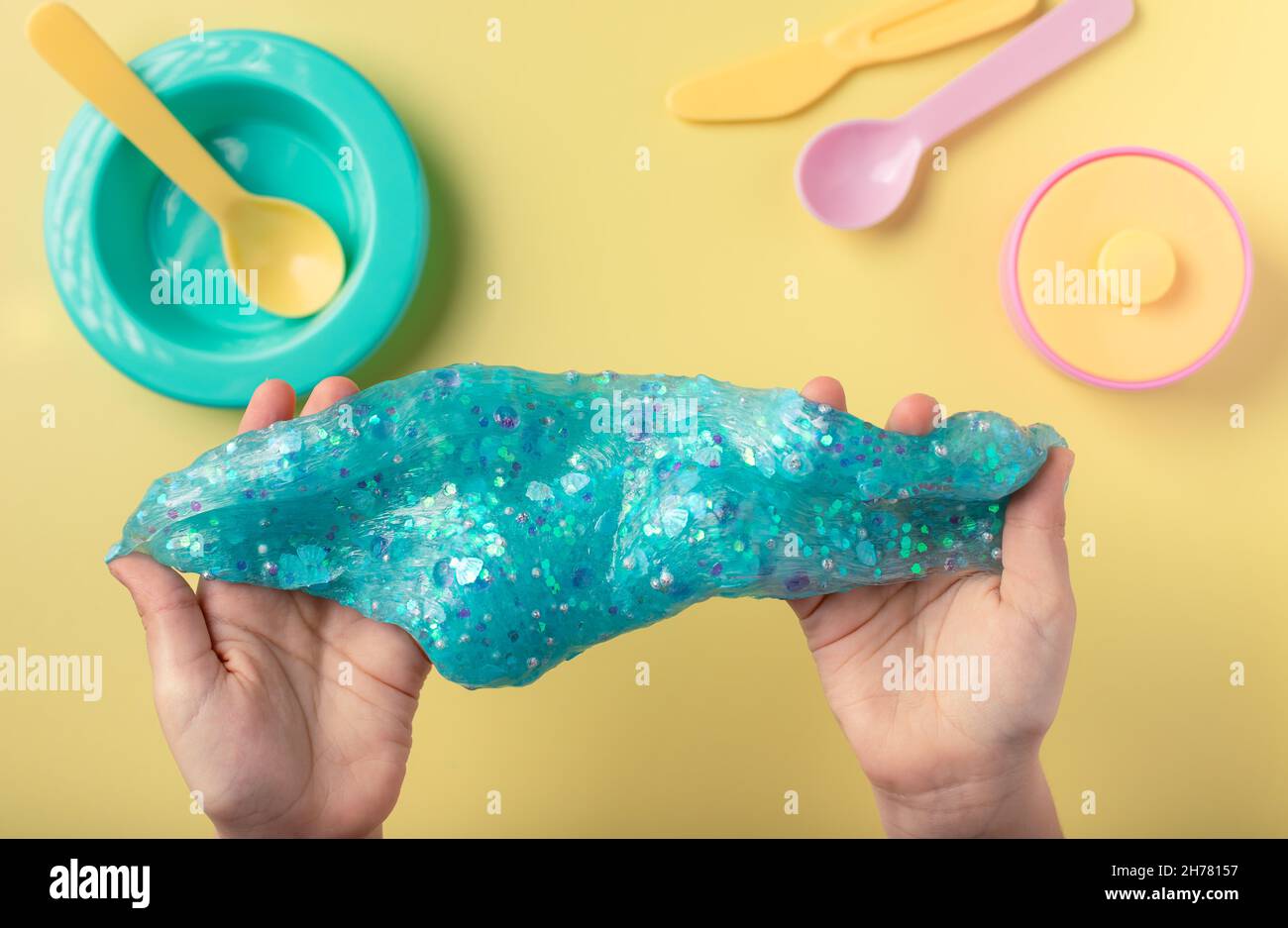 blue glitter slime in childrens hands on yellow background Stock Photo ...