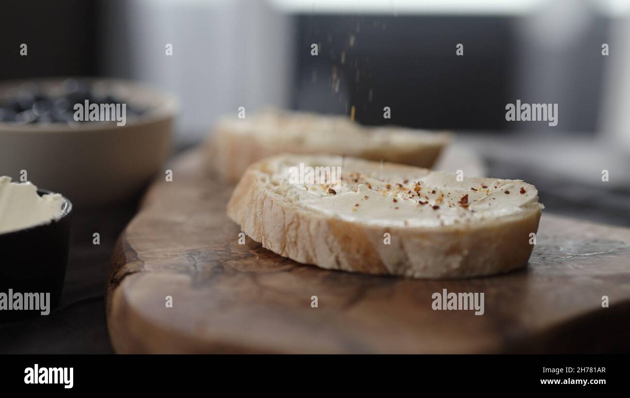 grind spices on cream cheese on slice of ciabatta, wide photo Stock ...