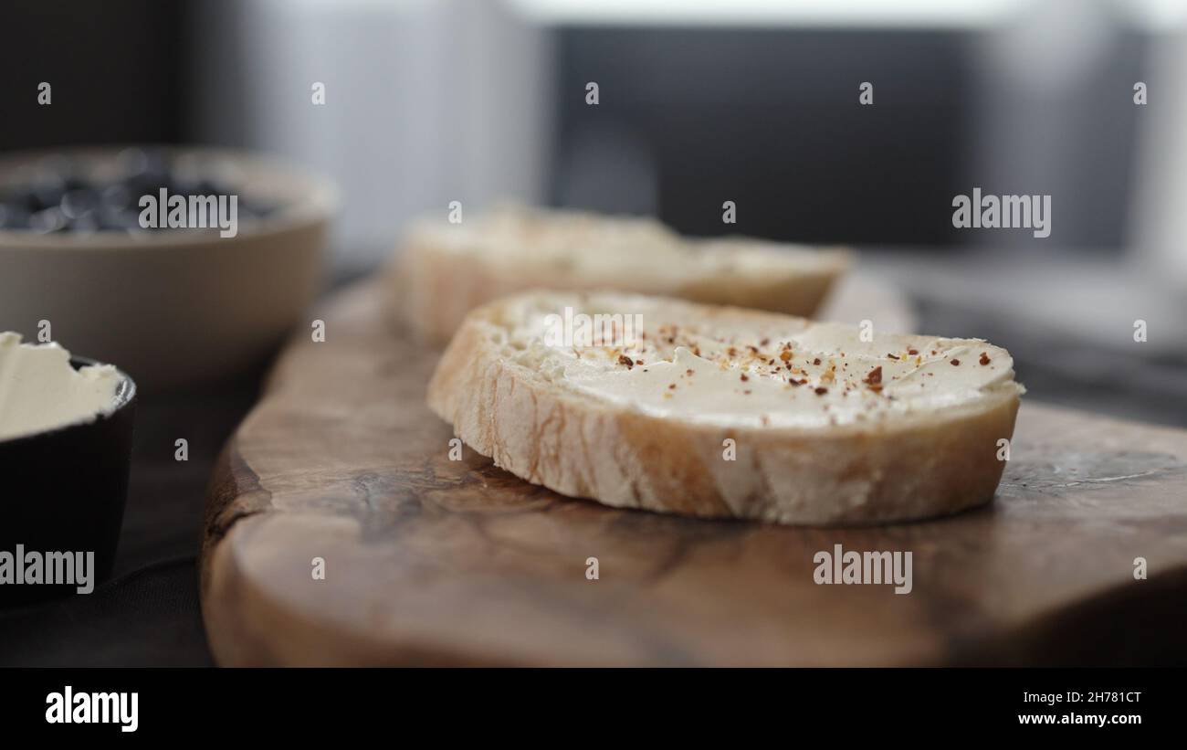 grind spices on cream cheese on slice of ciabatta, wide photo Stock ...