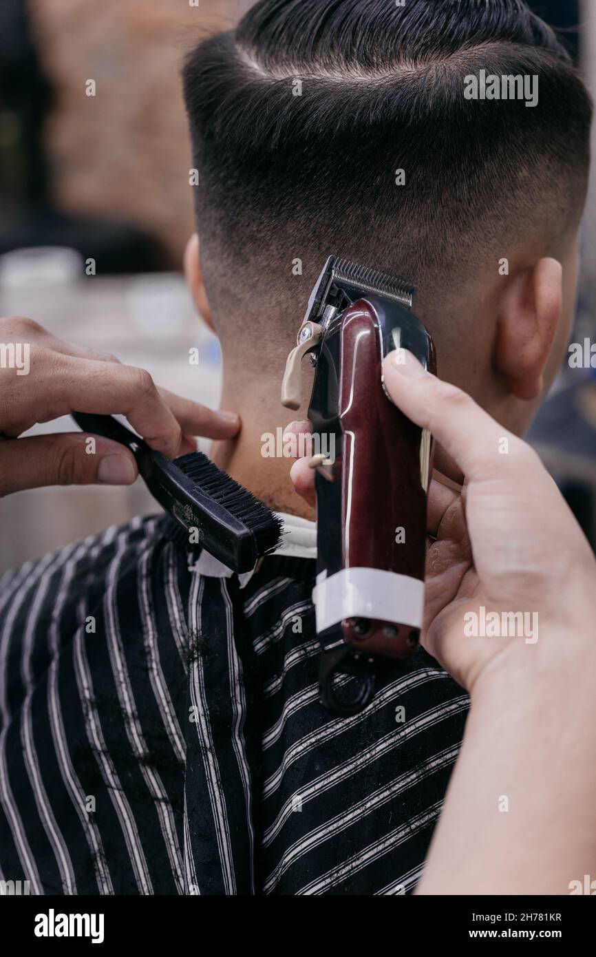barber using hair clipper and comb to cut the hair in the barber shop ...
