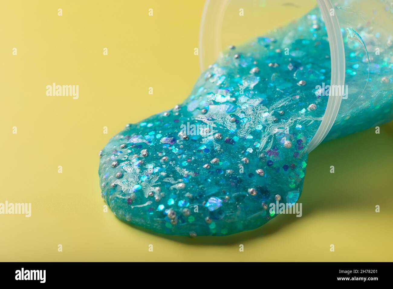 blue slime with glitter flows from plastic container Stock Photo - Alamy