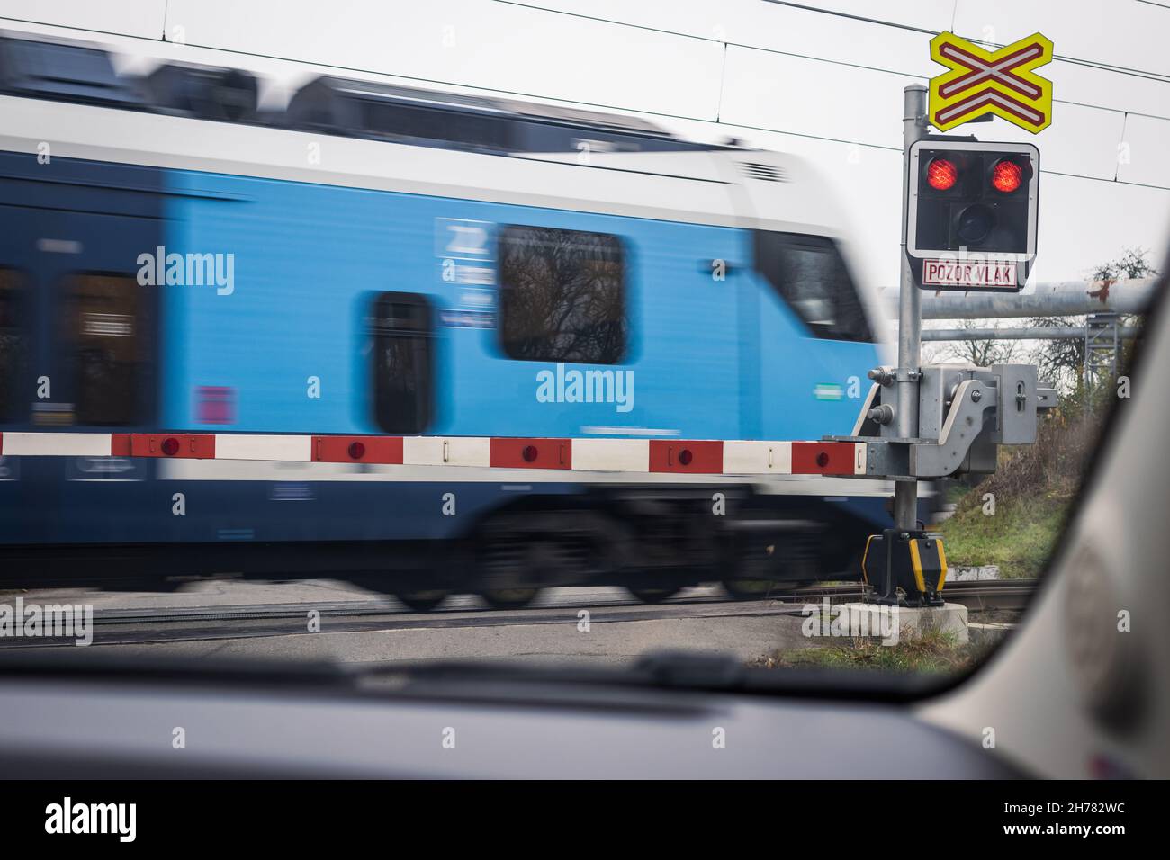 Train passing through railroad crossing at road. Looking from car ...