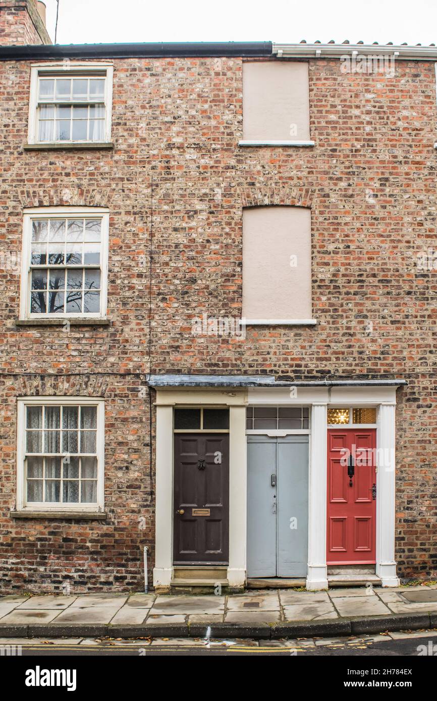 Facade of traditional British brick terraced houses with colorful doors ...